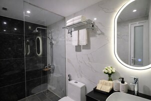 Um banheiro moderno com chuveiro em gabinete de vidro, pia branca e toucador com amenities.