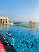 Piscina infinita com vista clara para o oceano e montanhas distantes.