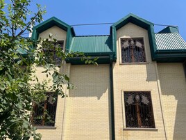 Um edifício com telhado verde e duas janelas ornamentadas com grades de metal.