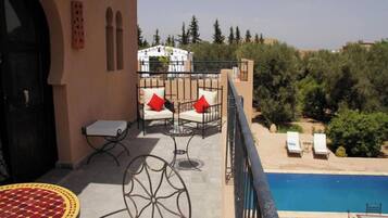 Uma varanda com piscina, área de estar ao ar livre e vista para árvores e edifícios.