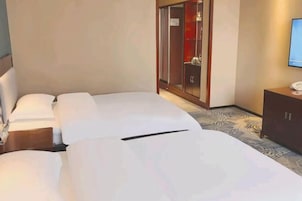 Quarto de hotel com duas camas, um guarda-roupa, uma escrivaninha com telefone e uma televisão.
