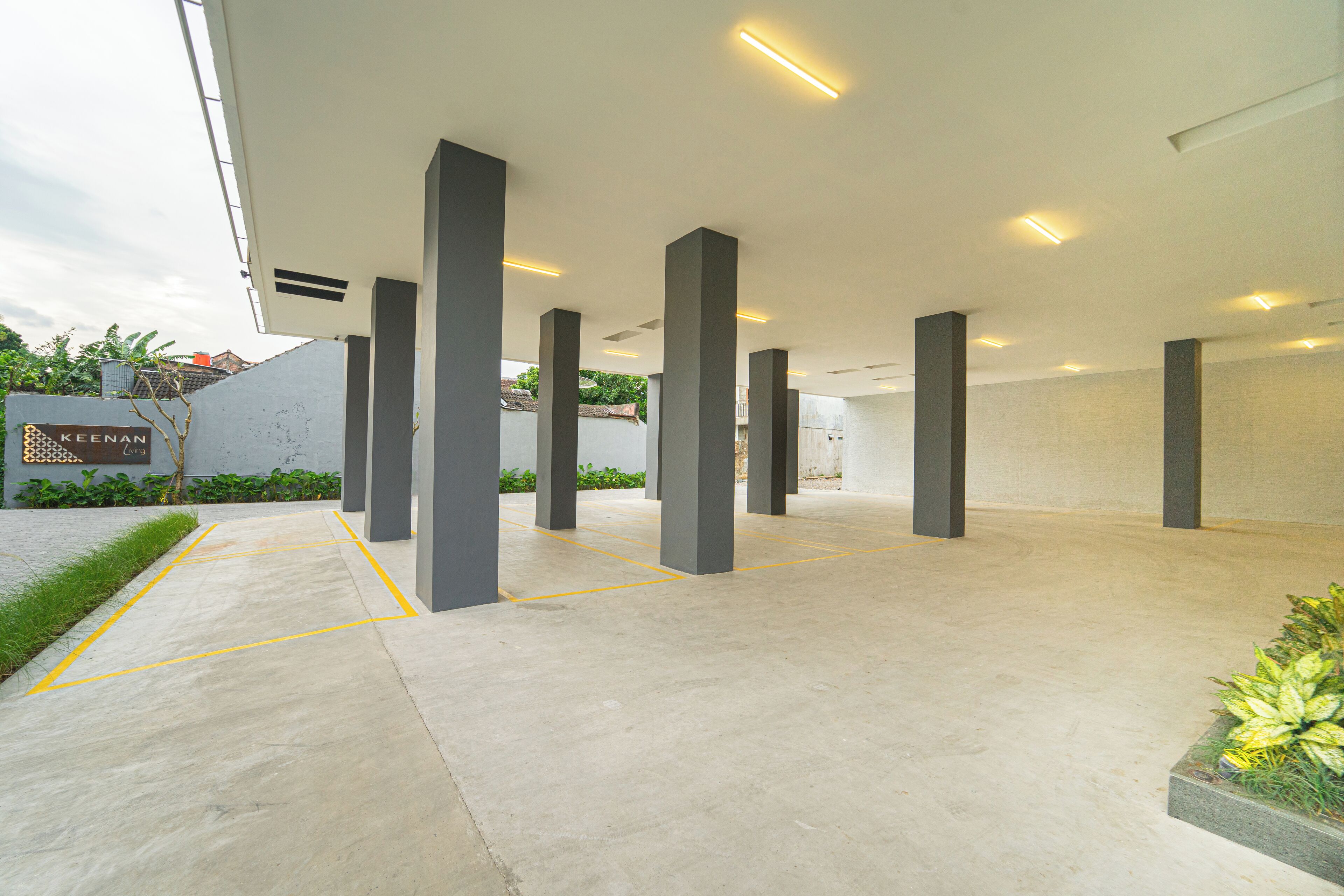 Um espaço amplo e interno, com piso de concreto e pilares grandes, com uma placa que diz "KEENAN".