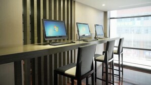 Uma área de bar moderna com três monitores de computador, balcão de madeira e cadeiras pretas.