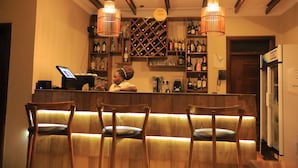 Uma área de bar com cadeiras de madeira, um balcão e uma estante para vinhos.