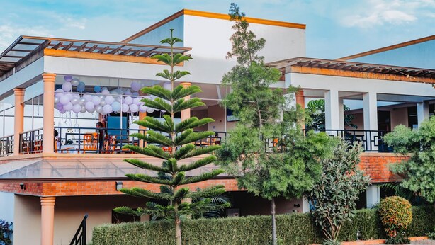 Um edifício moderno com fachada de vidro, várias varandas e um terraço no telhado.