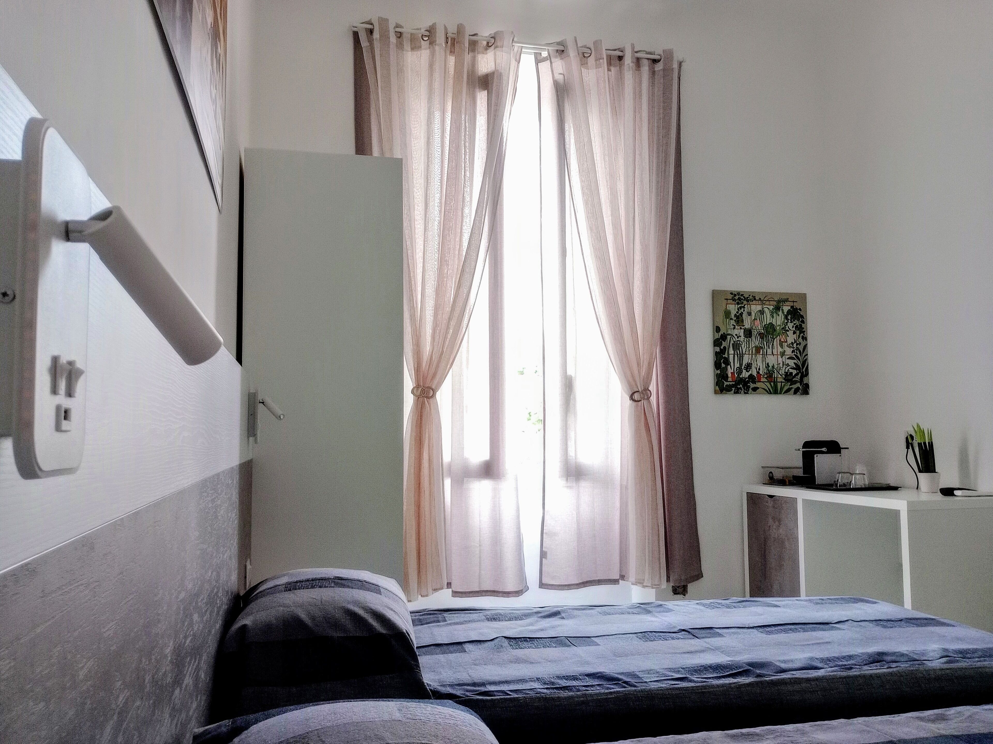 Quarto com cama, escrivaninha e janela com cortinas.