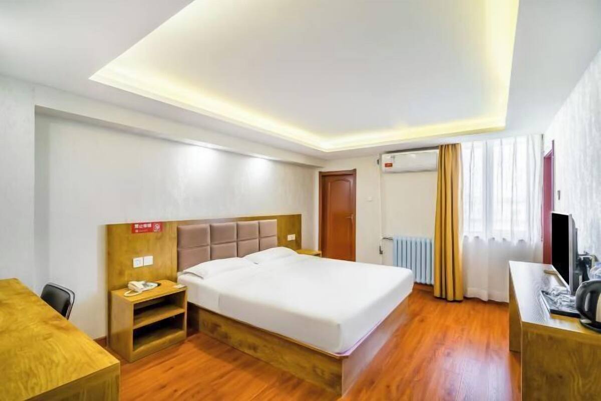 Quarto de hotel com cama, escrivaninha, cadeira, telefone e televisão.