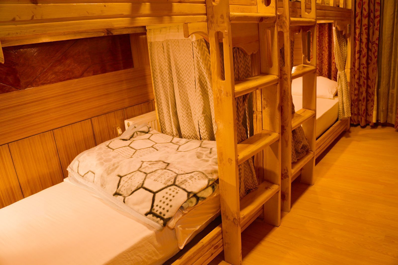 Quarto com beliches, paredes de madeira e colcha estampada.
