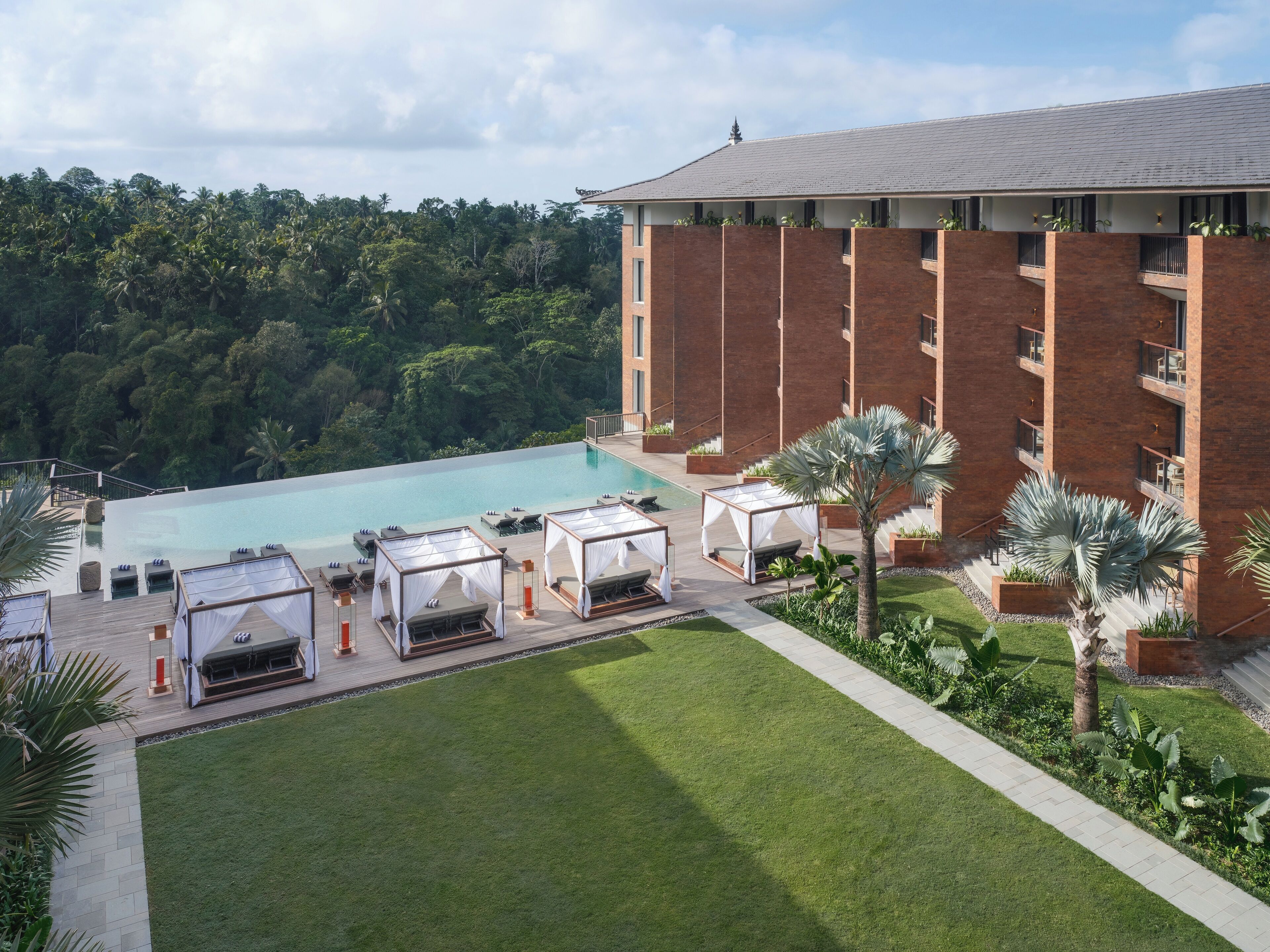Um hotel com piscina, área de estar externa e um jardim exuberante.