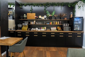 Uma cozinha moderna com armários pretos, bancadas de madeira e uma máquina de café embutida. Há diversos utensílios e objetos decorativos nas prateleiras.