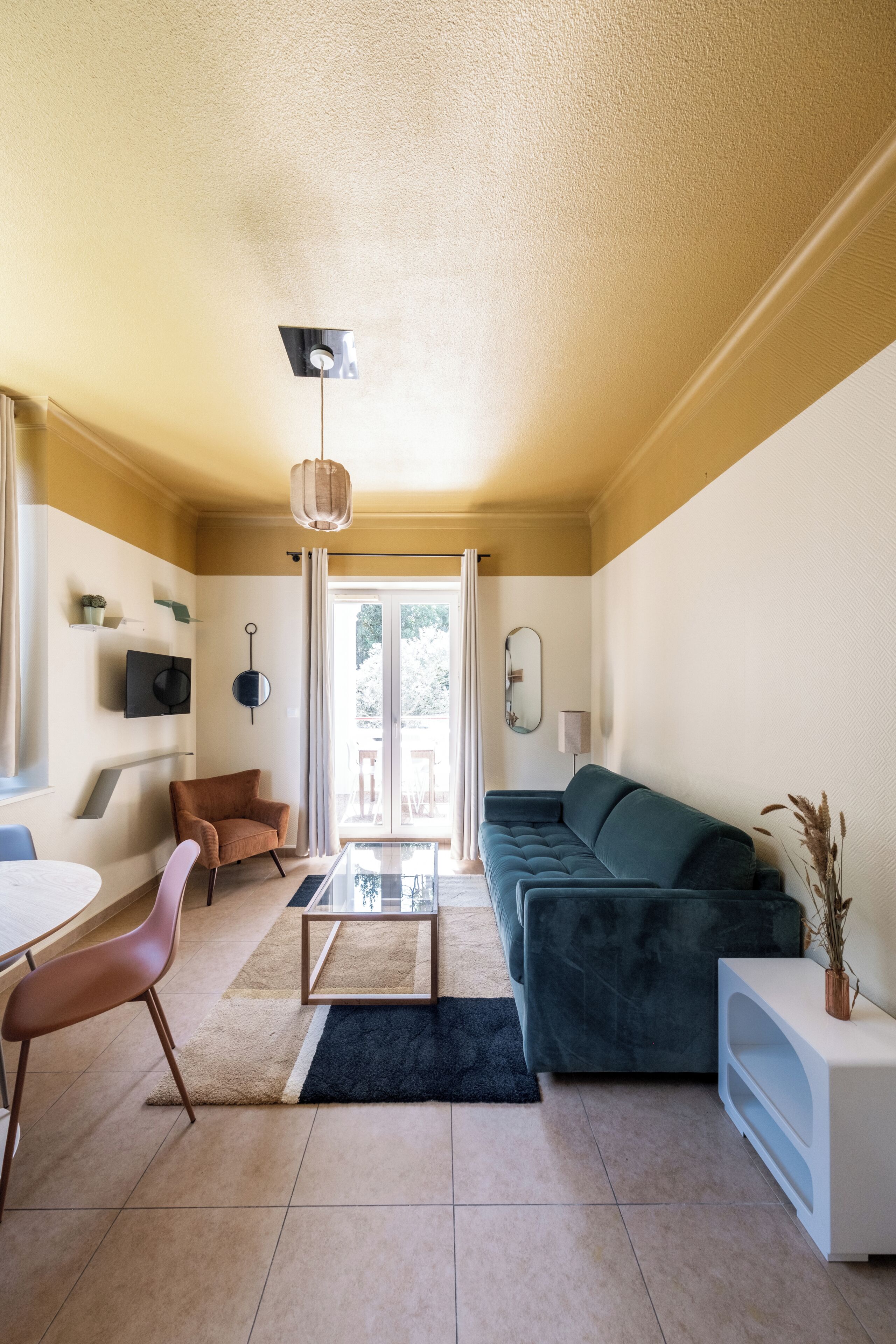 Uma sala de estar moderna com um sofá, uma mesa de centro, um espaço de refeições com cadeiras e uma janela grande.