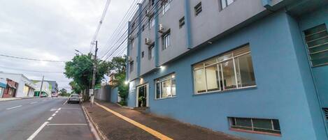Um edifício com fachada azul, várias janelas e calçada pavimentada.