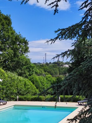 Piscina rodeada por vegetação exuberante e um céu azul límpido.