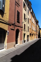 Rua com edifícios com arcadas e céu claro.