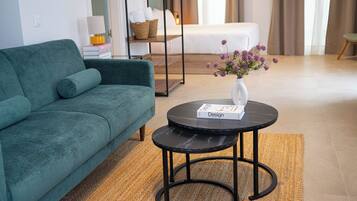 Uma sala de estar moderna com um sofá verde-água, uma mesa de centro redonda preta com um livro intitulado "Design" e um vaso com flores roxas.