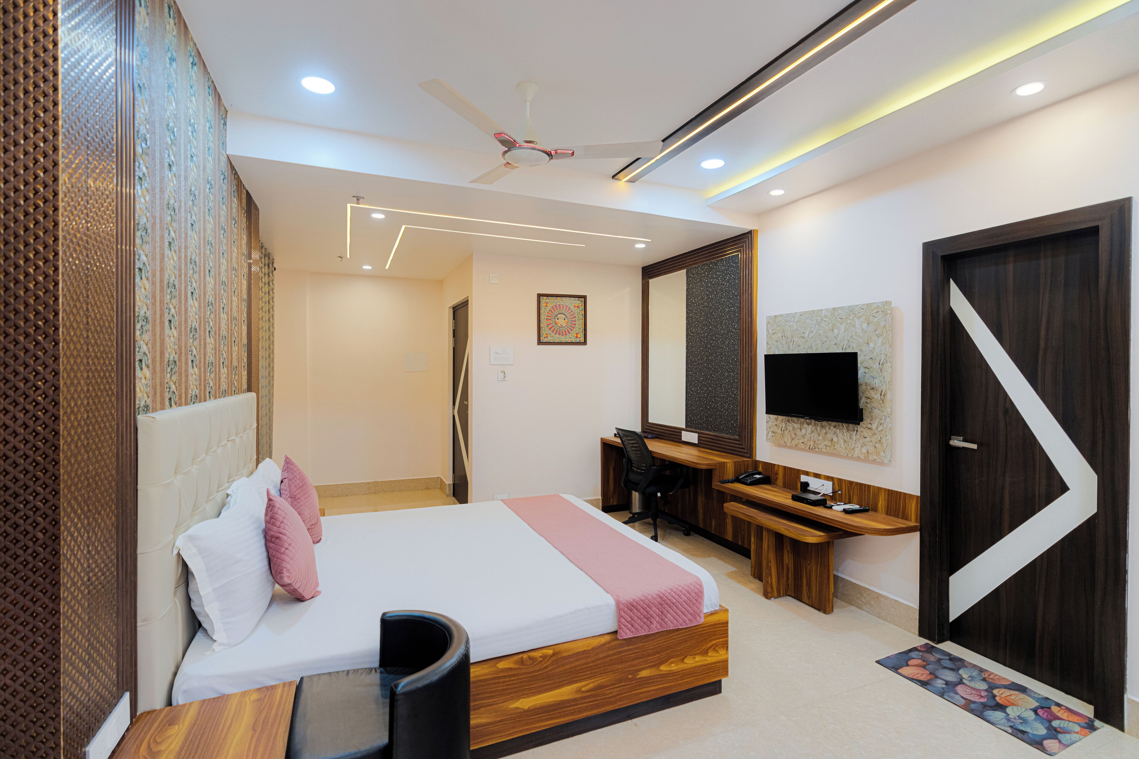Quarto moderno com cama, escrivaninha e televisão na parede.