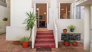 Uma escadaria que leva a um espaço interno com plantas em vasos e uma parede branca.