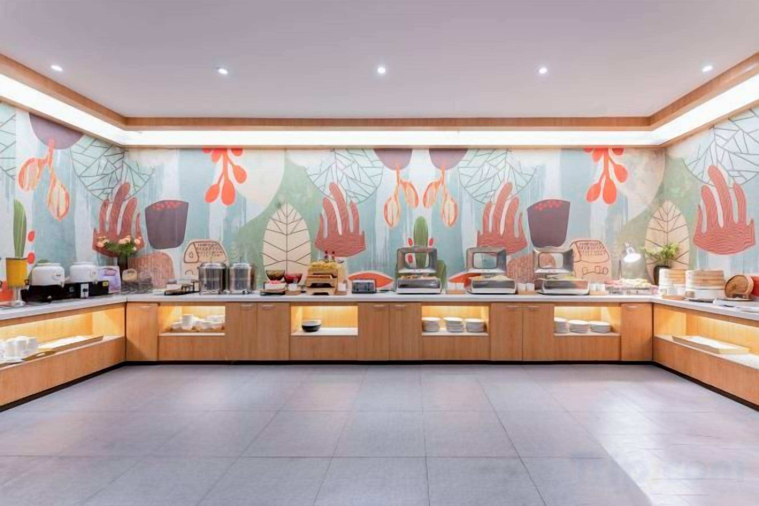 Um balcão de pequeno-almoço com diversas opções de comida e bebida, um grande mural na parede e chão revestido de azulejos.