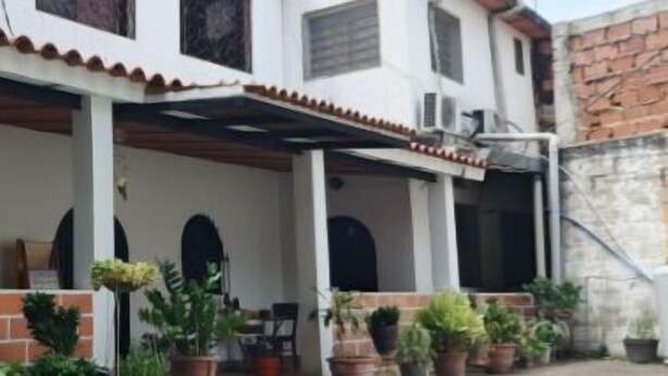 Um edifício com varanda coberta, várias janelas e plantas em vasos.