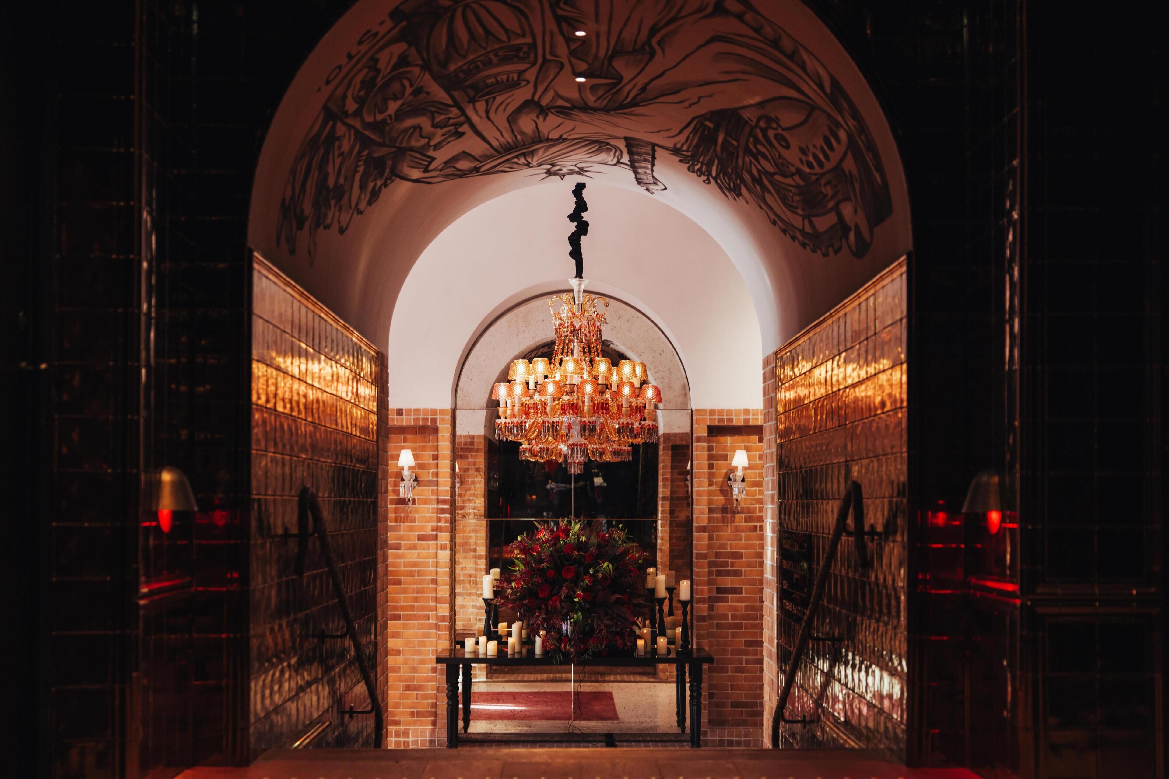 Um interior com um candelabro, paredes de tijolo e um arranjo floral.