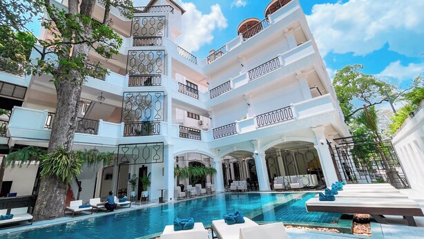 Um hotel com vários andares, piscina, área de estar ao ar livre e uma cascata.