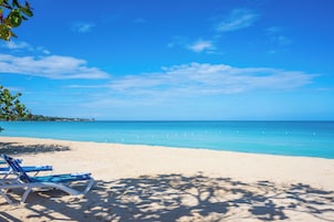 Na praia, areia branca, espreguiçadeiras