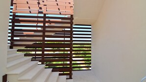 Escada com design de ripas de madeira que leva a uma varanda.