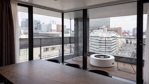 Uma sala de conferência moderna com uma mesa grande e cadeiras, amplas janelas com vista para a cidade e uma área de estar circular.