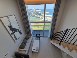Uma sala de estar moderna com uma grande janela, um sofá, uma mesa de centro e uma escada.