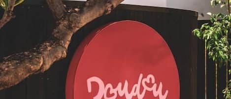 Um sinal vermelho circular com o texto "Dondra Hotel" ao fundo de uma cerca de madeira.