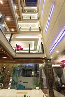 Interior com vários níveis, corrimãos de vidro, escada e iluminação moderna.
