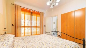 Quarto com cama, cortinas, guarda-roupa e um candelabro.