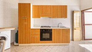 Uma cozinha compacta com armários de madeira, forno embutido e pia.