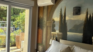 Quarto de hotel com uma cama grande, vista para o exterior e um mural decorativo na parede.