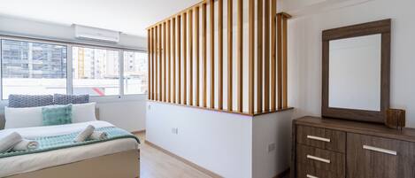 Um quarto moderno com cama, mesa de cabeceira e uma janela grande.