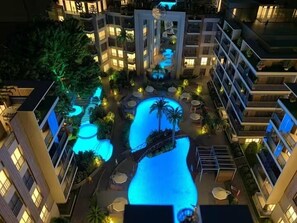 Um hotel com vários andares, piscina central, áreas de estar ao ar livre e um pátio bem iluminado.