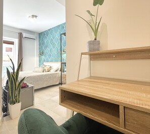 Quarto com cama, mesa de cabeceira e um vaso de planta.