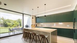Uma cozinha moderna com uma ilha grande, banquetas e vista para o exterior.