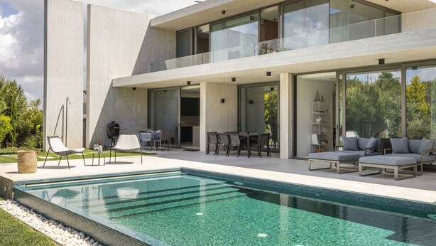 Uma casa moderna de dois andares com piscina, área de estar externa e janelas amplas.