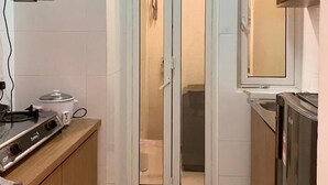 Cozinha pequena com fogão, um ventilador e geladeira.