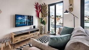 Sala moderna com televisão de tela plana, painel de entretenimento de madeira e uma janela grande com vista para a cidade.