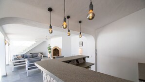 Cozinha moderna com ilha central, iluminação pendente e escada que dá para uma sala de estar.