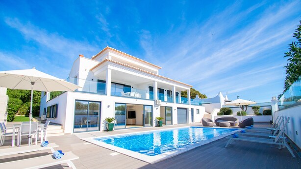 Uma casa moderna com piscina, área de estar externa e um grande portão de vidro.