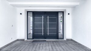 Uma entrada moderna com porta dupla e um tapete pequeno no limiar.