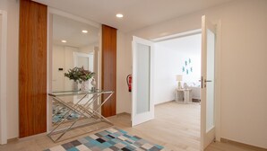 Um corredor moderno com uma mesa de vidro, detalhes em madeira e um tapete estampado.
