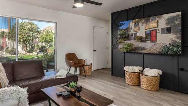 Uma sala de estar moderna com uma televisão grande, sofá de couro e um ventilador de teto.