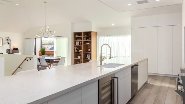 Cozinha moderna com ilha central, forno embutido e área de jantar com mesa e cadeiras.