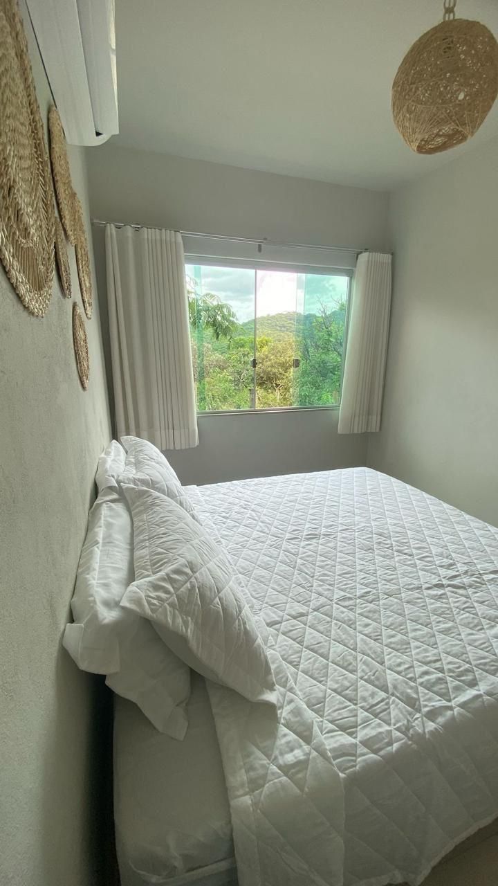 Quarto com uma cama, janela com cortinas e ar condicionado fixado na parede.