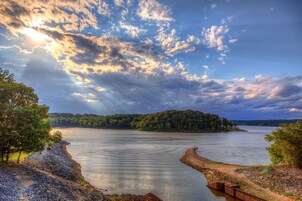 Um lago tranquilo com um cais de madeira e uma ilha arborizada ao longe.