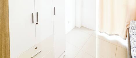 Um quarto claro e arejado, com um guarda-roupa, cortina de chuveiro e ar condicionado.